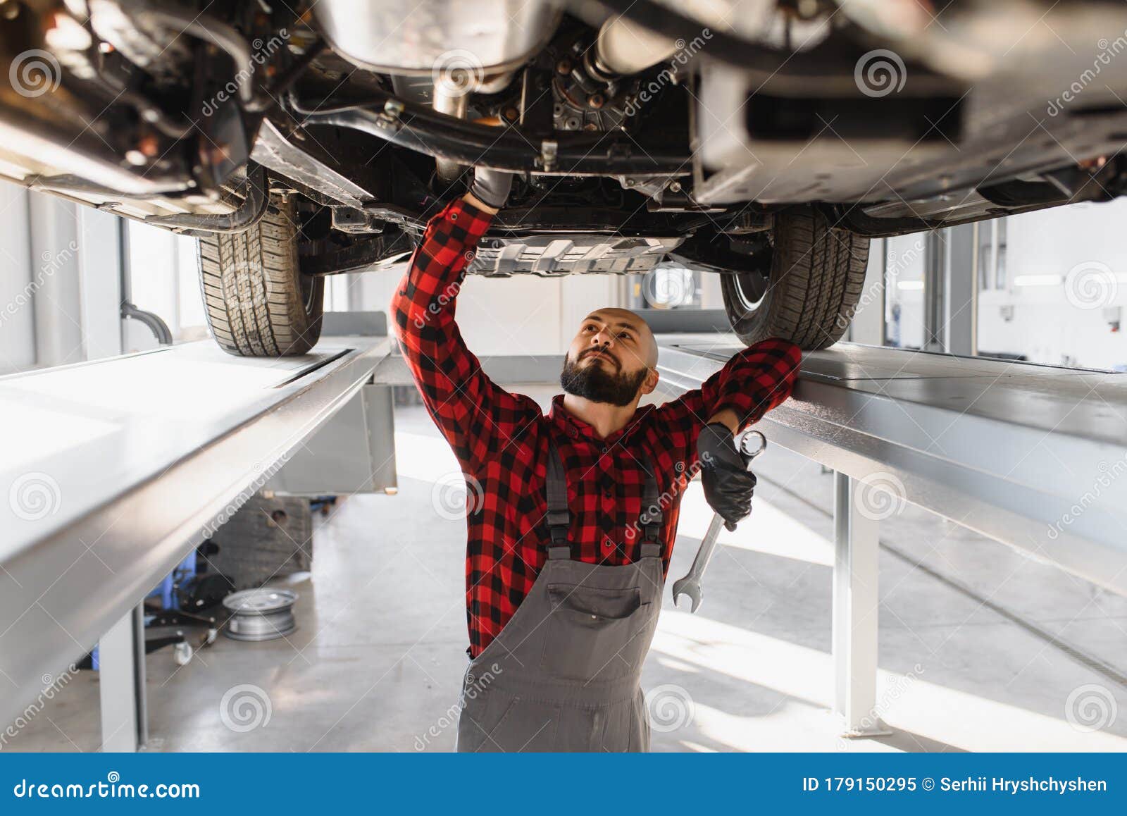 Mechanic Working Under Car at the Repair Garage. Auto Mechanic Working ...
