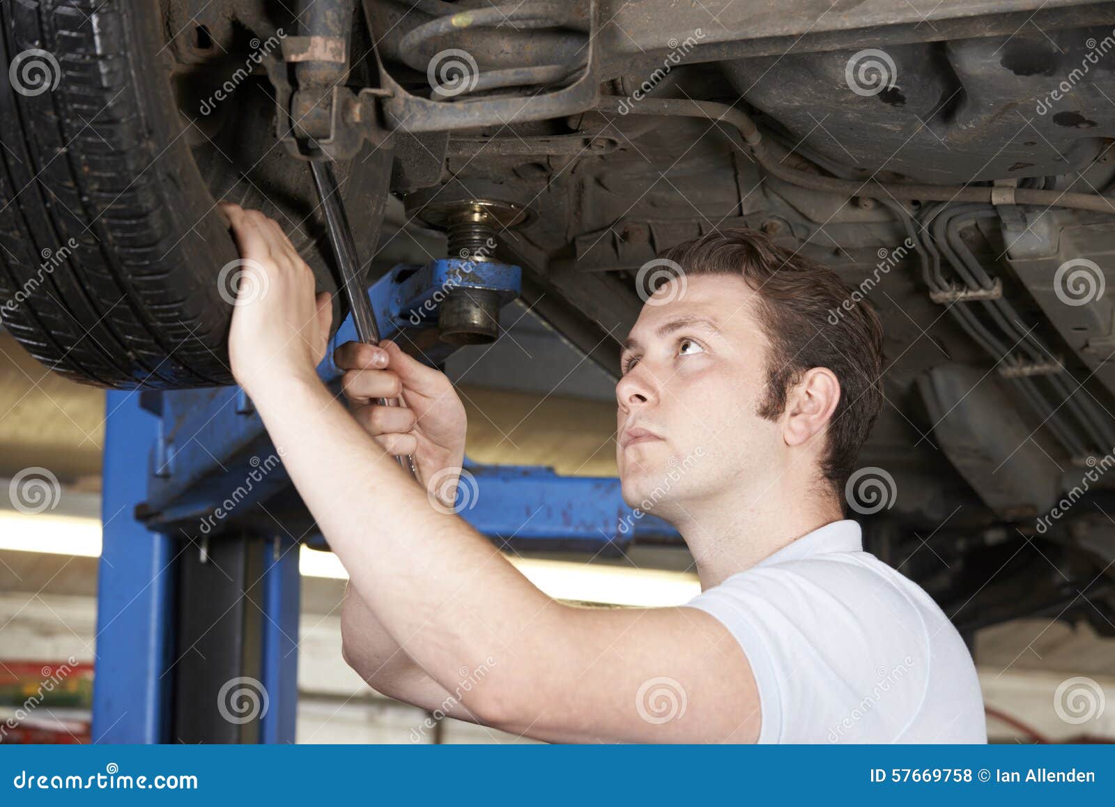 Mechanic Working on Wheel Underneath Car Stock Photo - Image of ...