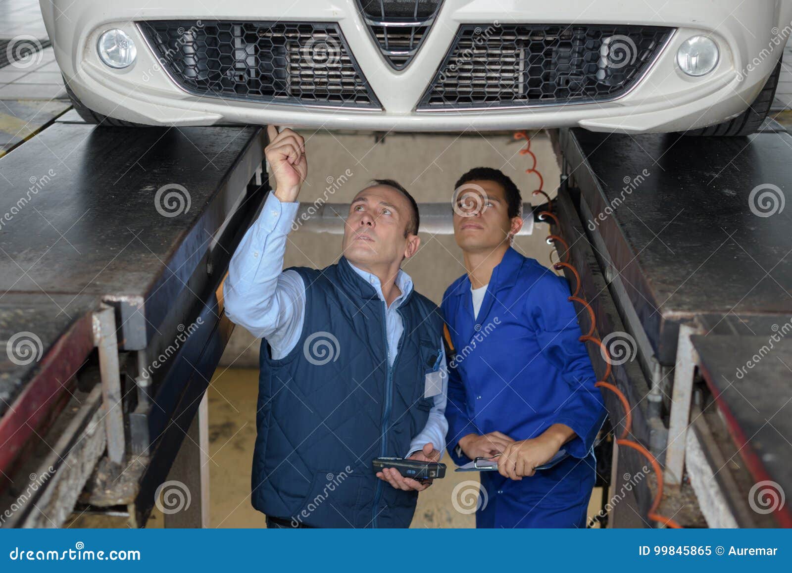 Mechanics Inspecting Vehicle Chassis On Lift In Garage Stock Photo ...