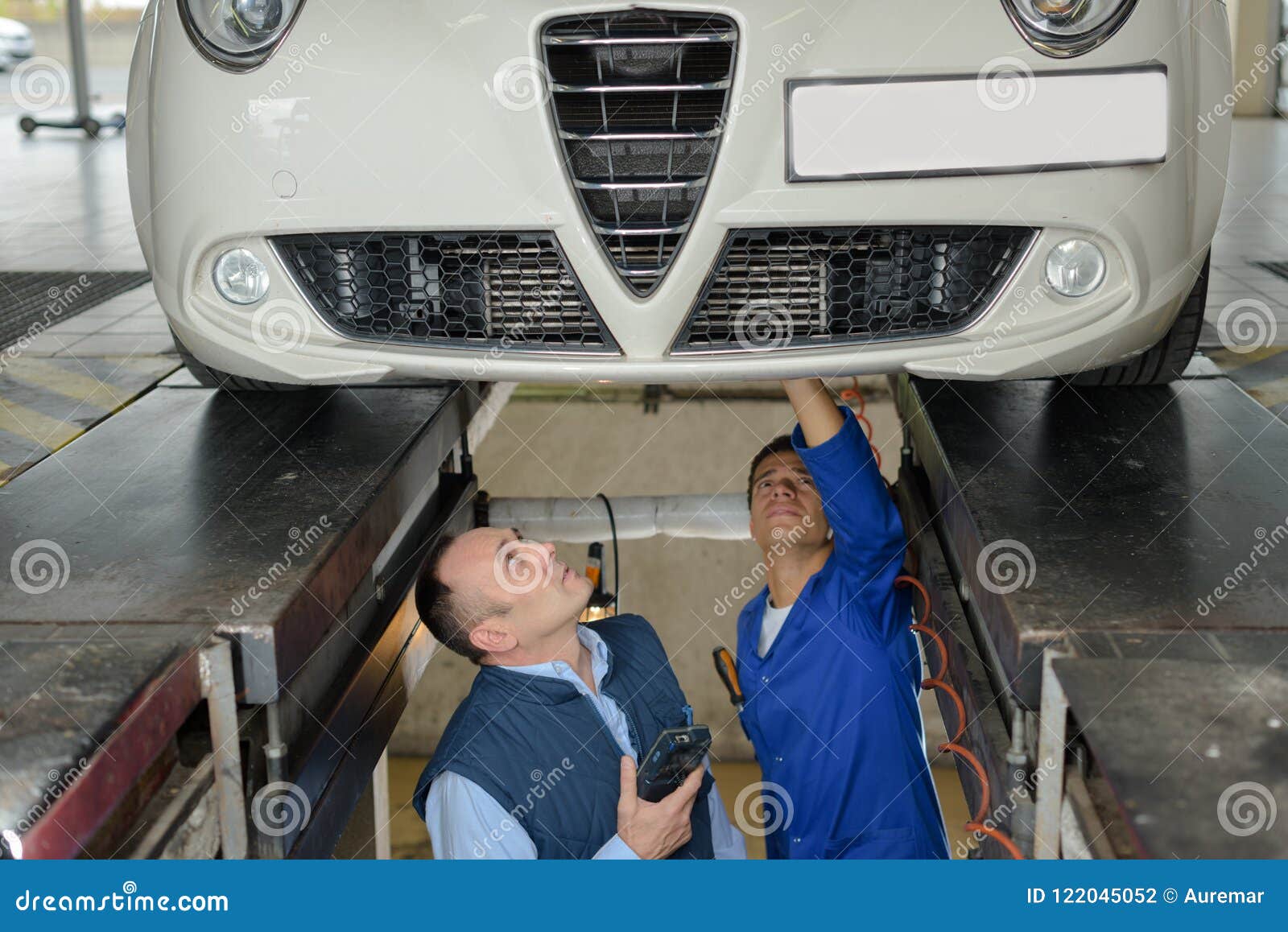 Mechanics in Pit Underneath Car Stock Photo - Image of inspector ...