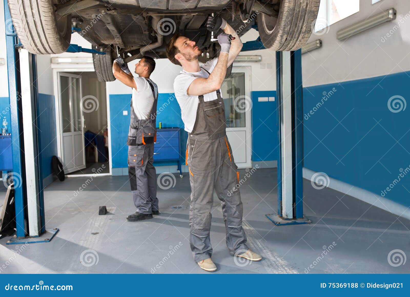 Mechanics Working Together Under the Car Stock Photo - Image of person ...