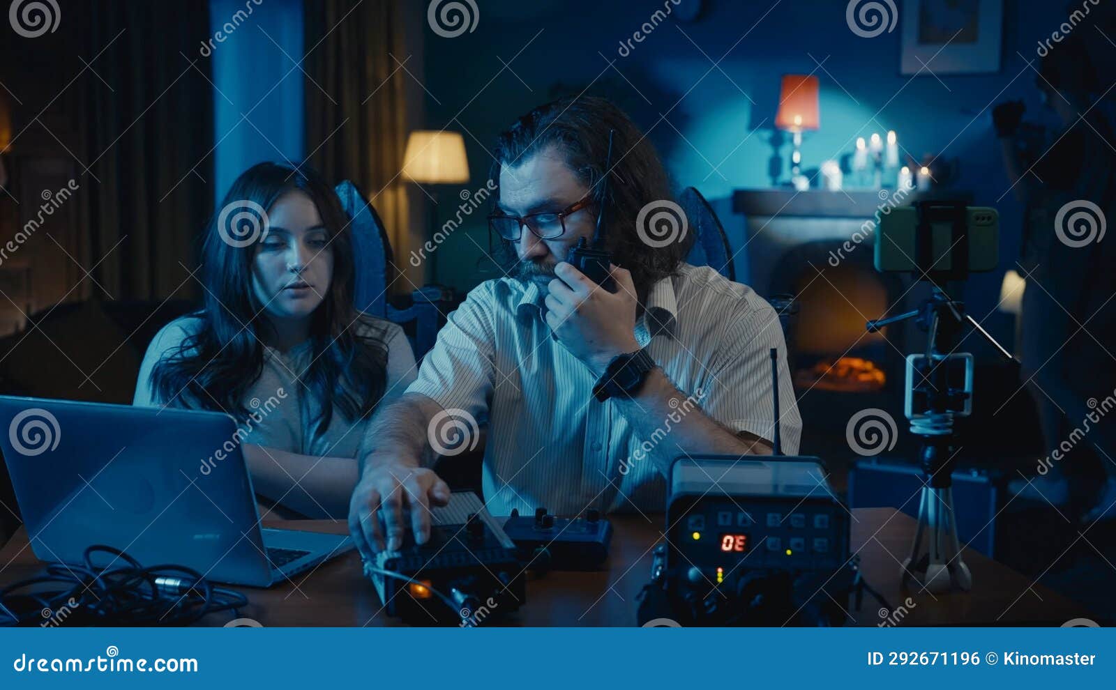 Medium-sized Photo of a Ghost Hunter and a Victim Sitting at the Table in a Dark Room. Another ...