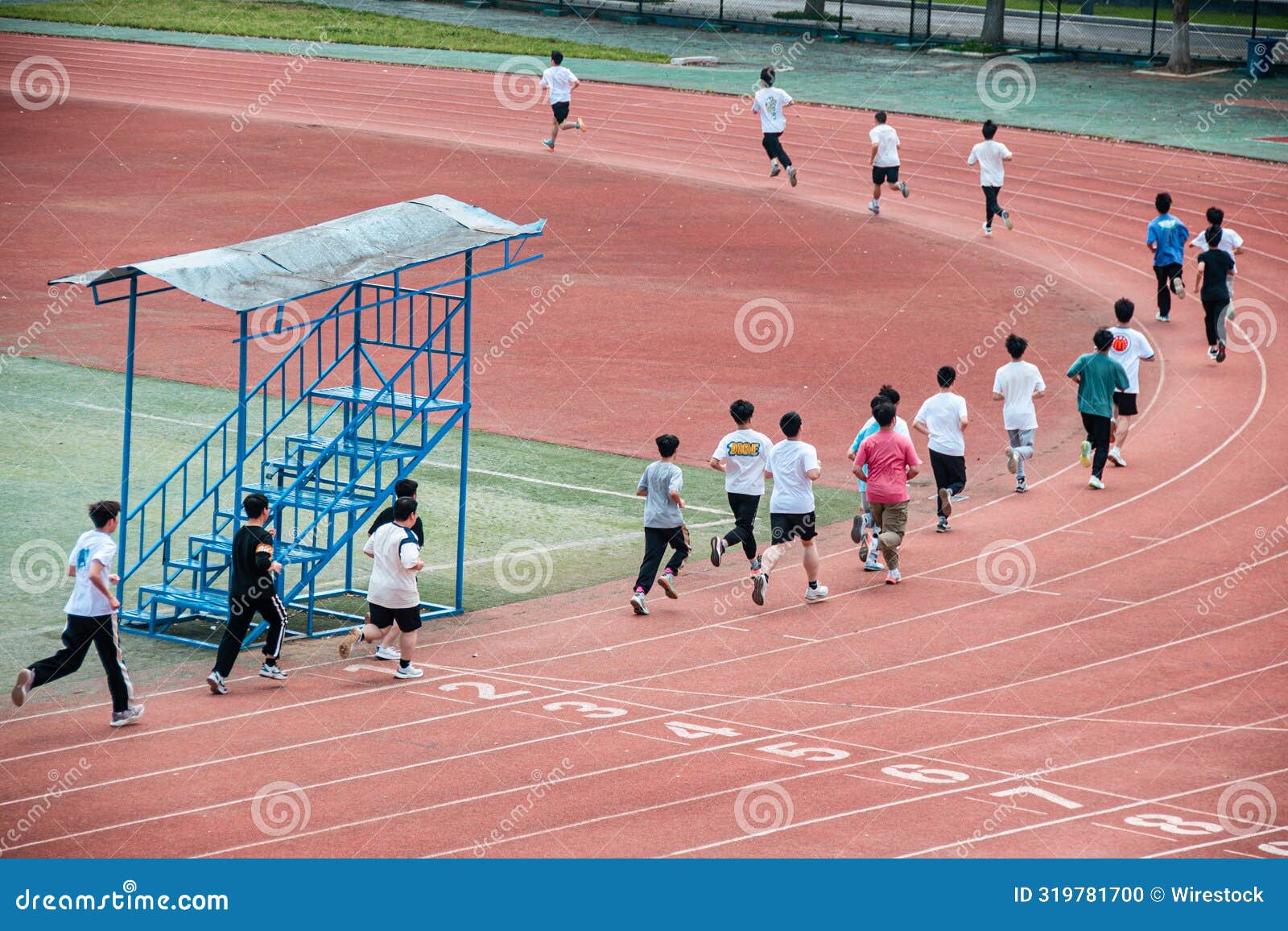 Men Running on a Track in an Empty Stadium, with a Blue Platform ...
