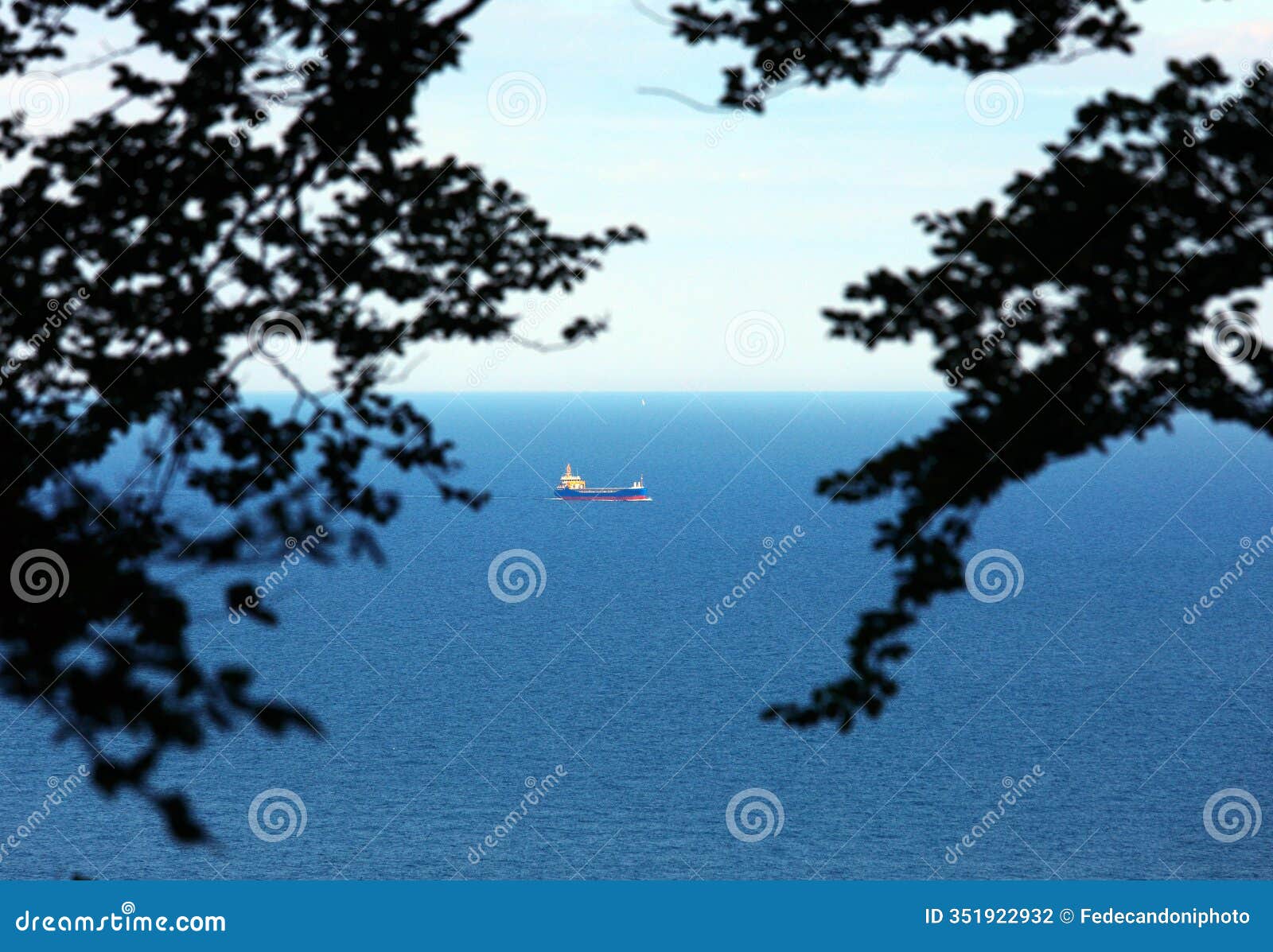 Merchant Ship Sails in the Middle of the Blue Sea between Two Branches ...