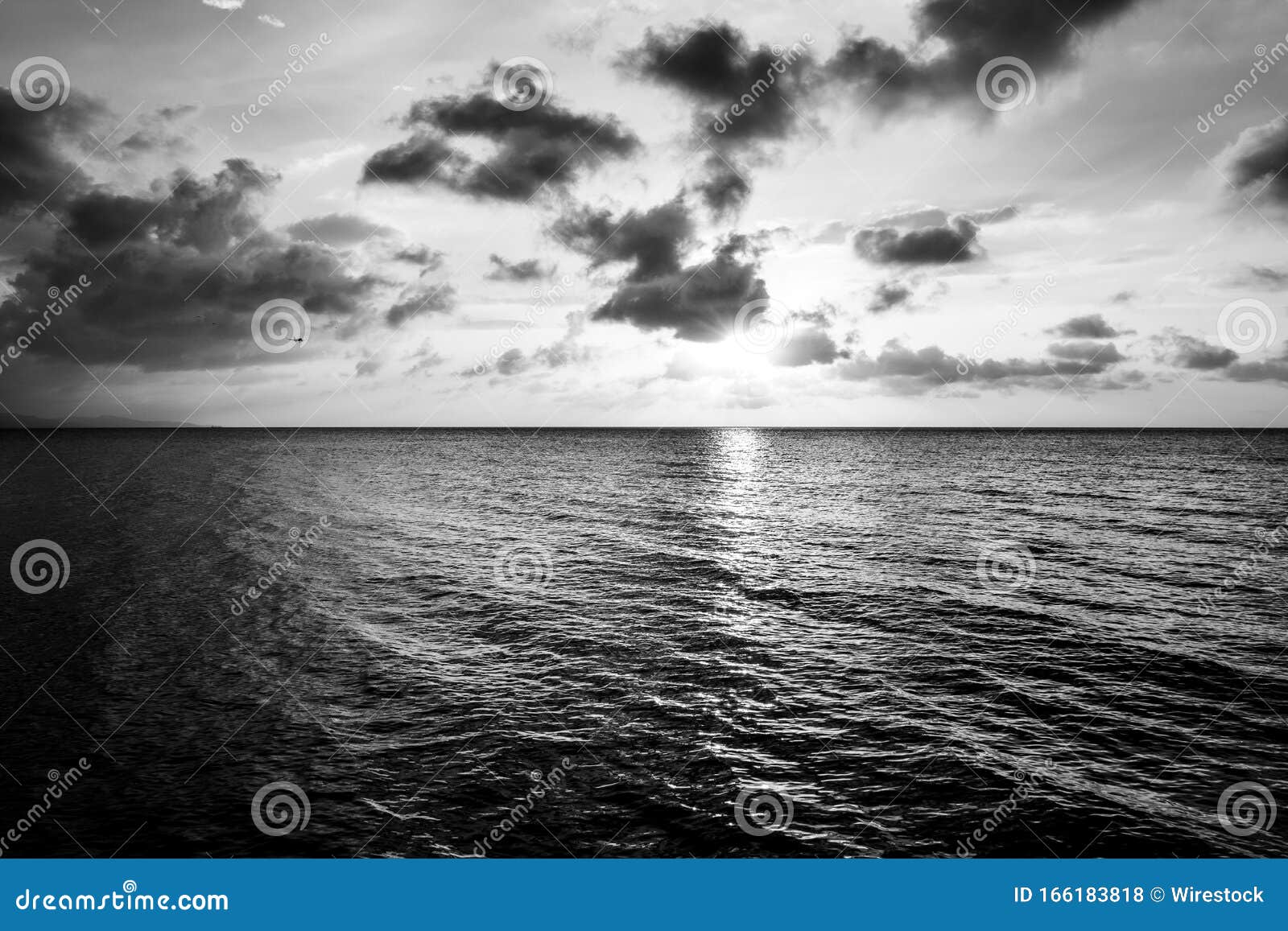 Mesmerizing Greyscale Shot of the Sun Setting Behind the Clouds Over ...