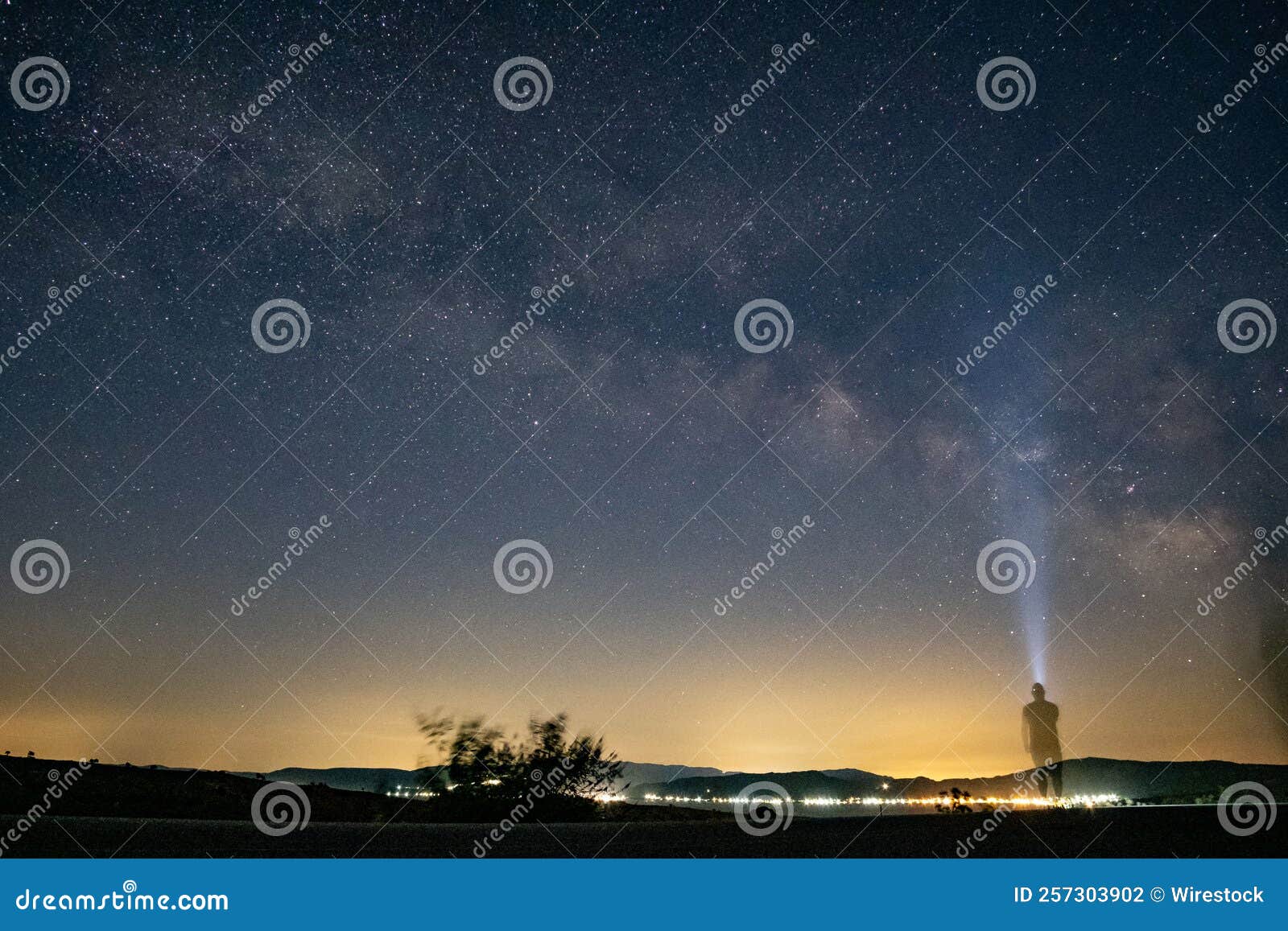 Mesmerizing Scene of a Man Pointing a Flashlight Towards the Night Sky ...