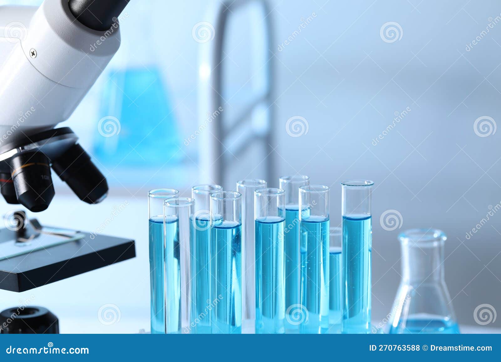 Microscope and Test Tubes with Light Blue Liquid in Laboratory, Closeup ...