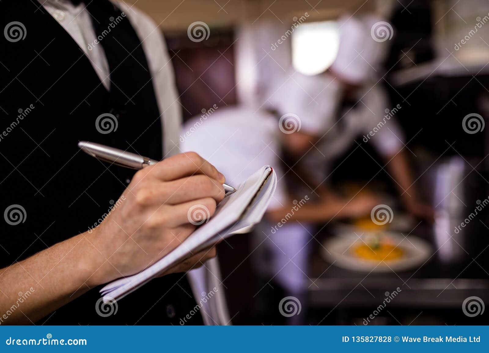 Female Waitress Noting an Order on Notepad in Kitchen Stock Photo ...