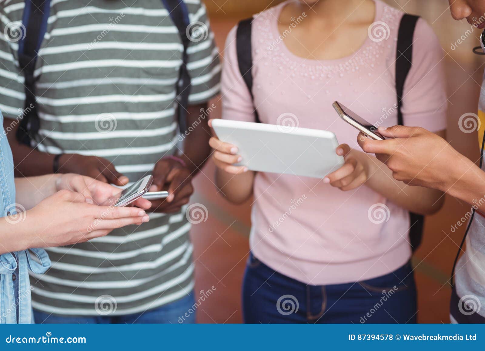 Mid Section of Students Using Mobile Phone and Digital Tablet in Campus ...
