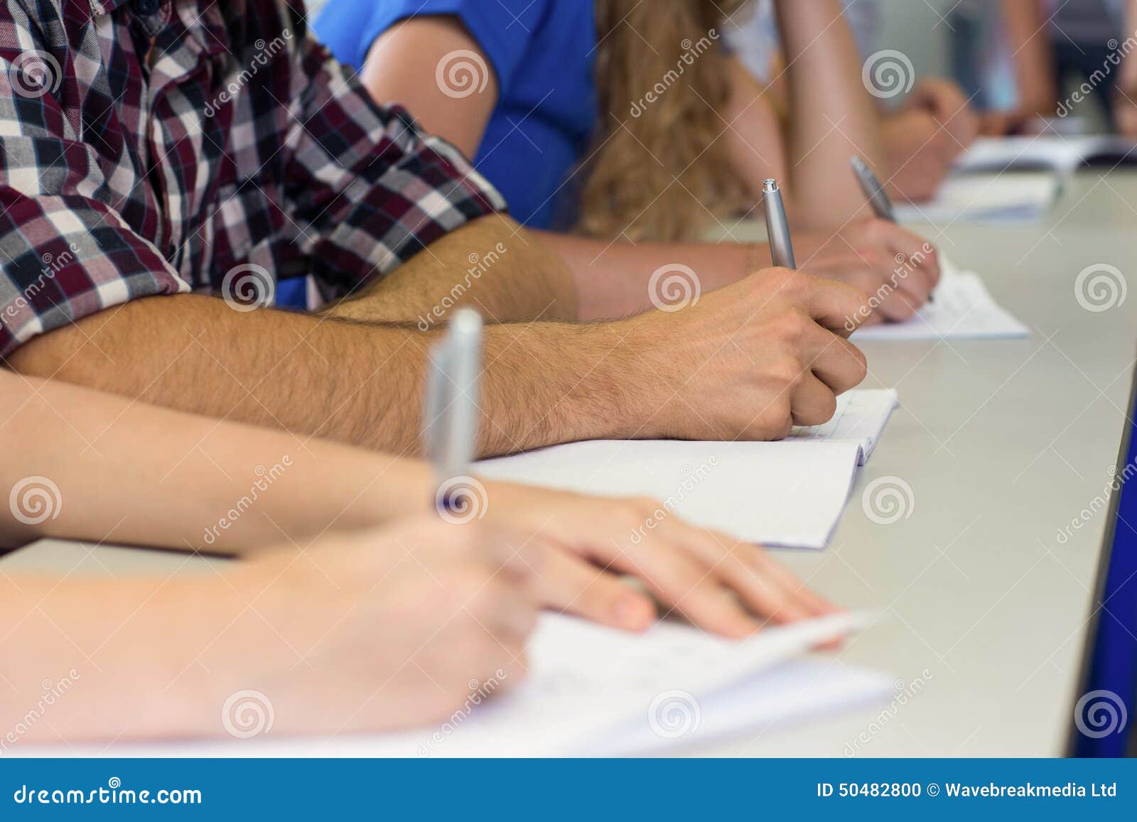 Mid Section of Students Writing Notes in Classroom Stock Photo - Image ...