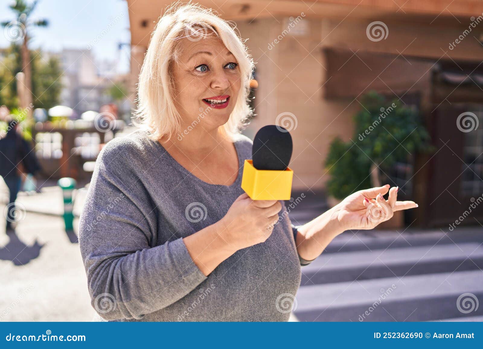 Middle Age Blonde Woman Reporter Working Using Microphone at Street ...