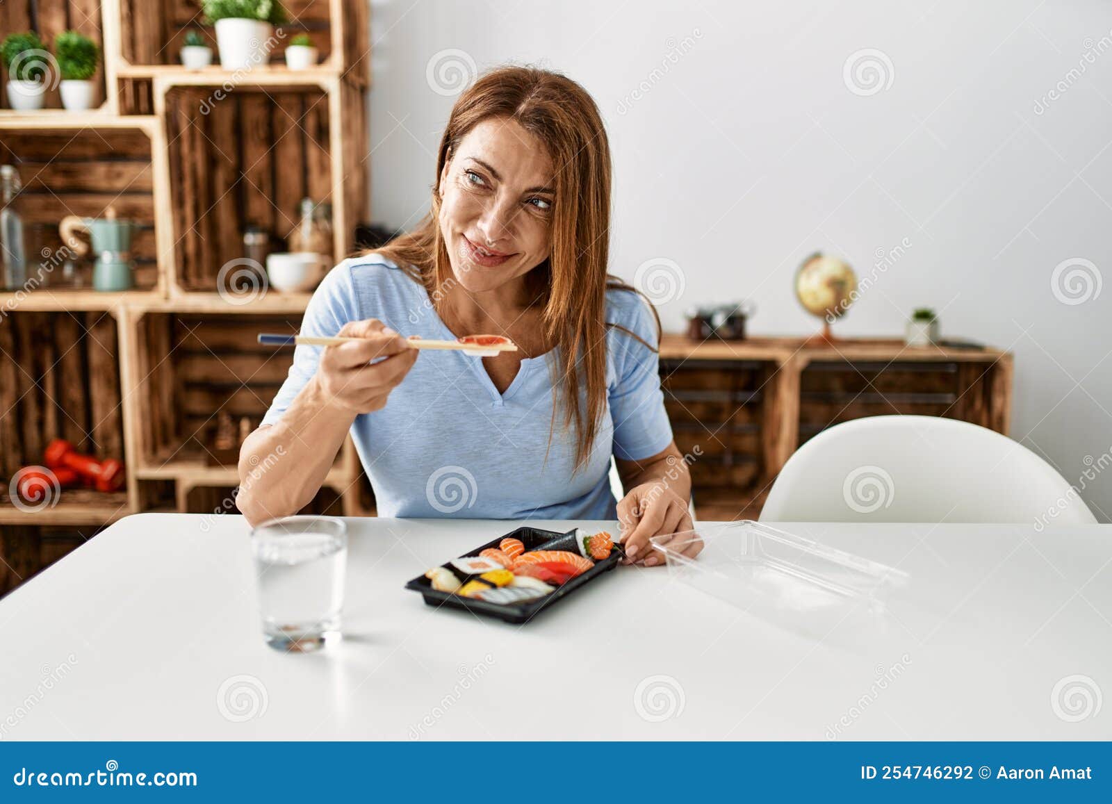 Middle Age Caucasian Woman Eating Sushi Sitting on the Table at Home ...