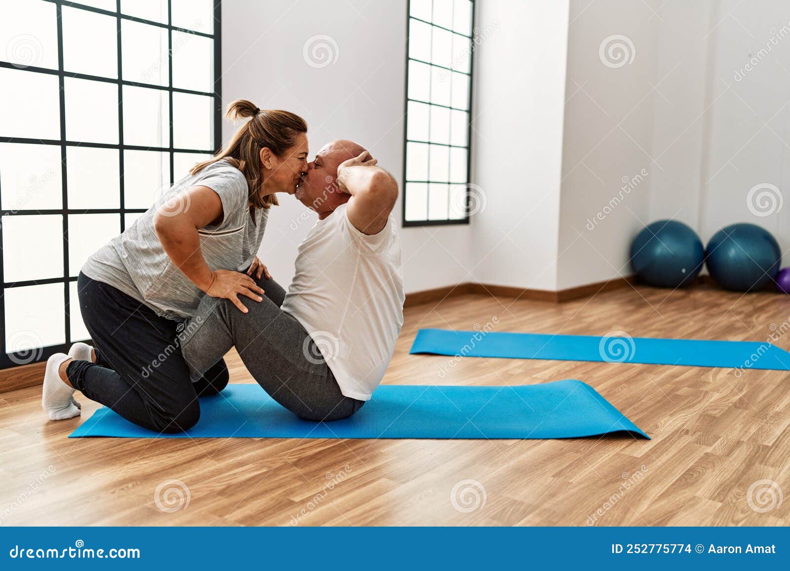 Middle Age Hispanic Couple Training Abs Exercise And Kissing At Sport