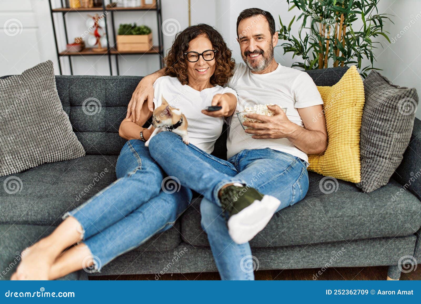 Middle Age Hispanic Couple Watching Movie And Eating Popcorn Sitting On