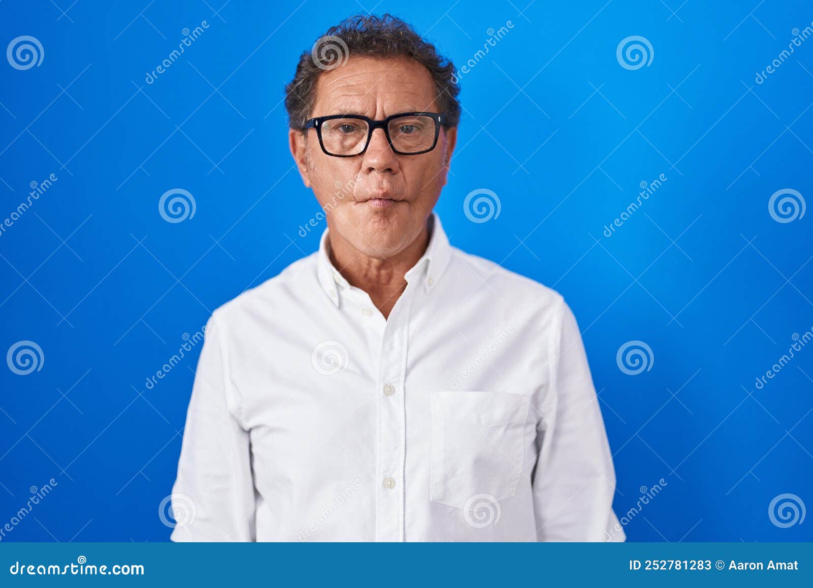 Middle Age Hispanic Man Standing Over Blue Background Making Fish Face ...