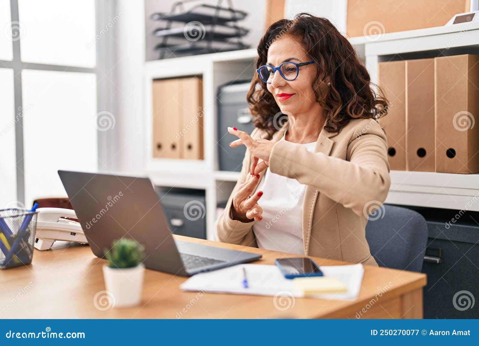 Middle Age Hispanic Woman Doing Video Call Using Sign Language at the ...