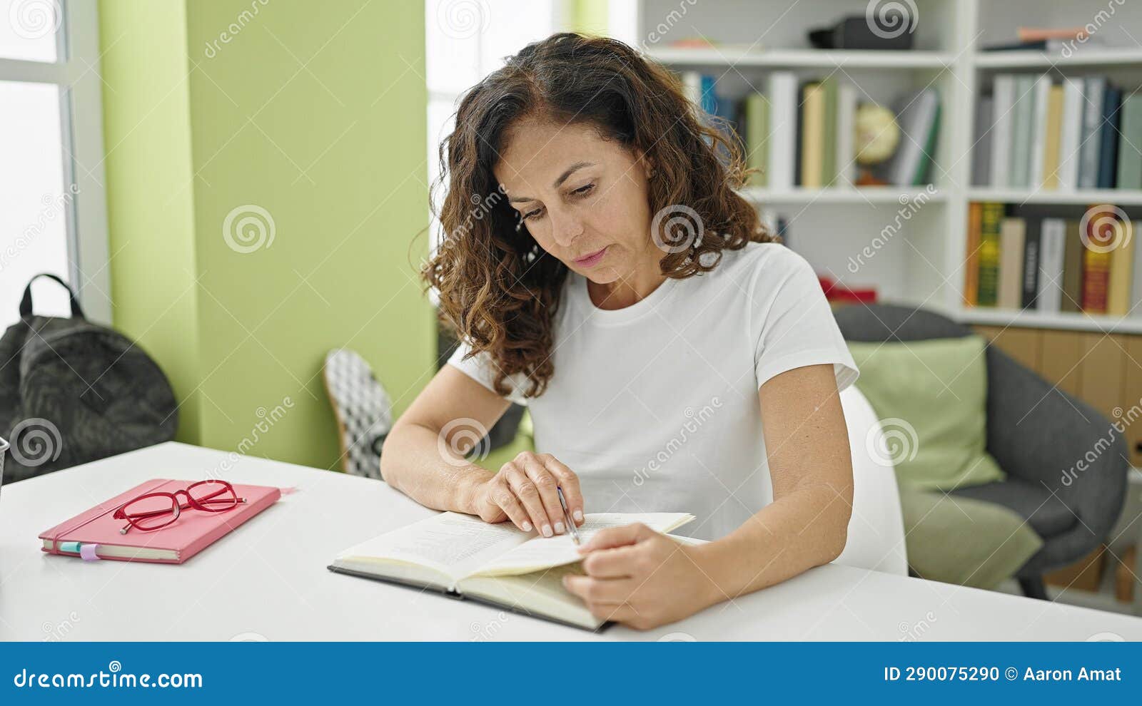 Middle Age Hispanic Woman Student Reading Book at Library University ...