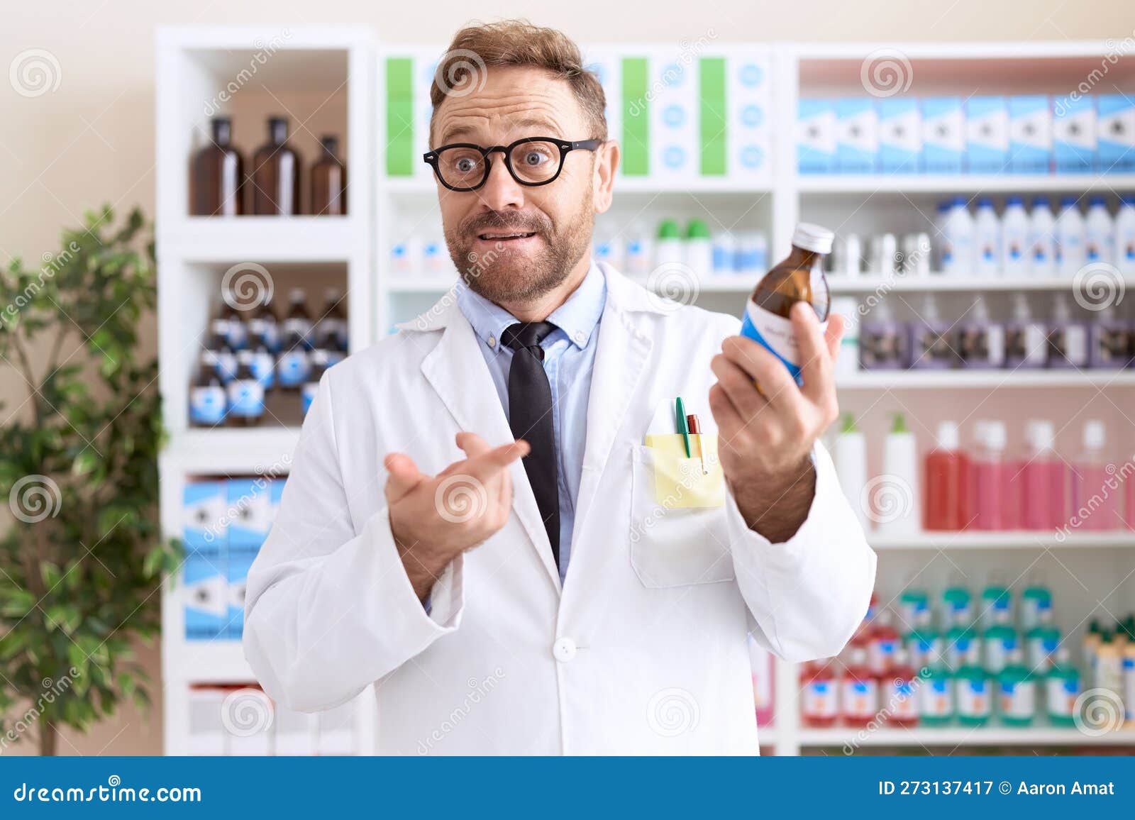 Middle Age Man Pharmacist Holding Medication Bottle Speaking at ...
