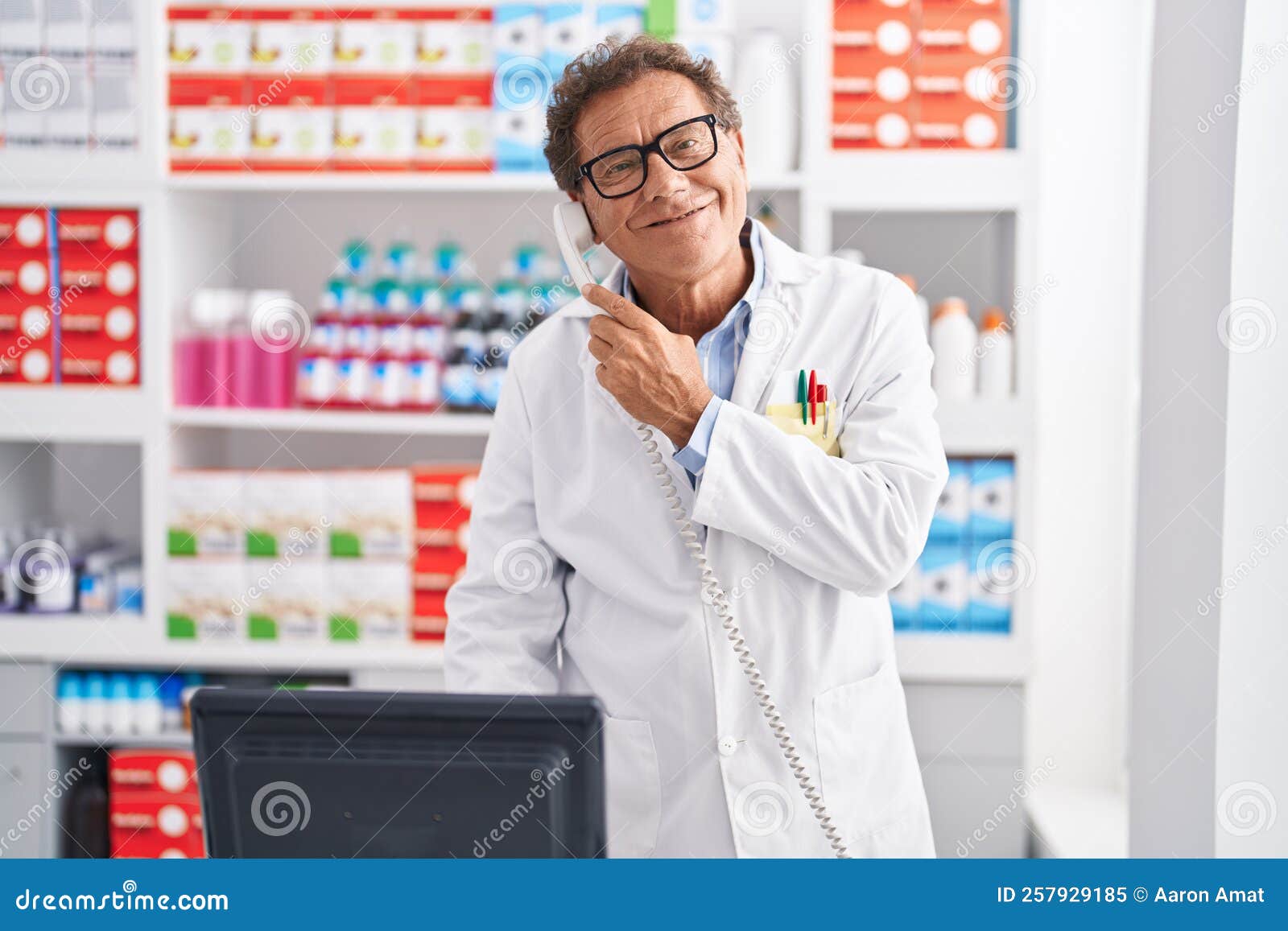 Middle Age Man Pharmacist Talking on Telephone Using Computer at ...