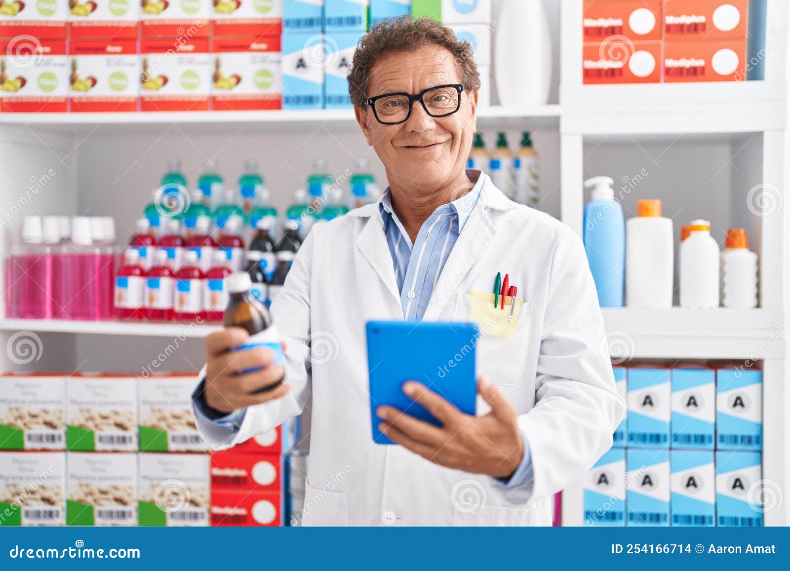 Middle Age Man Pharmacist Using Touchpad Holding Medicine Bottle at ...
