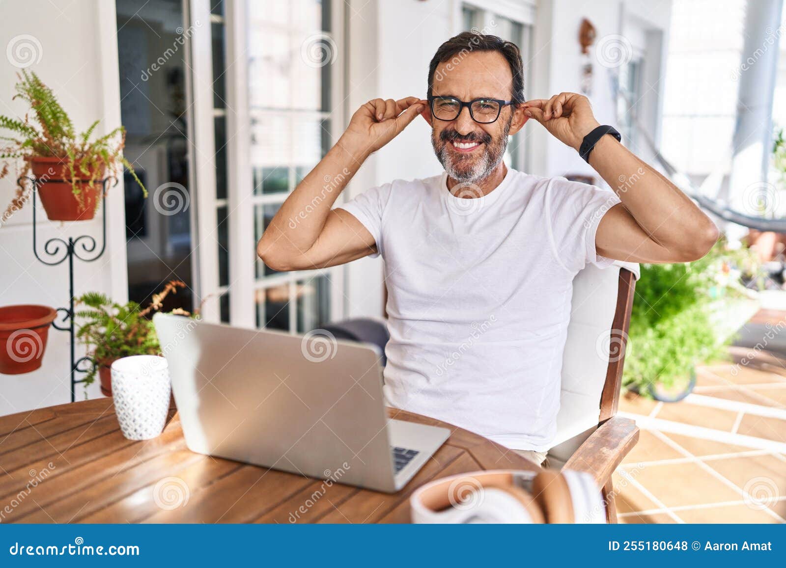 Middle Age Man Using Computer Laptop at Home Smiling Pulling Ears with ...