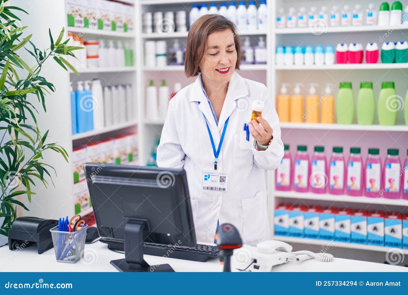 Middle Age Woman Pharmacist Using Computer Holding Pills Bottle at ...