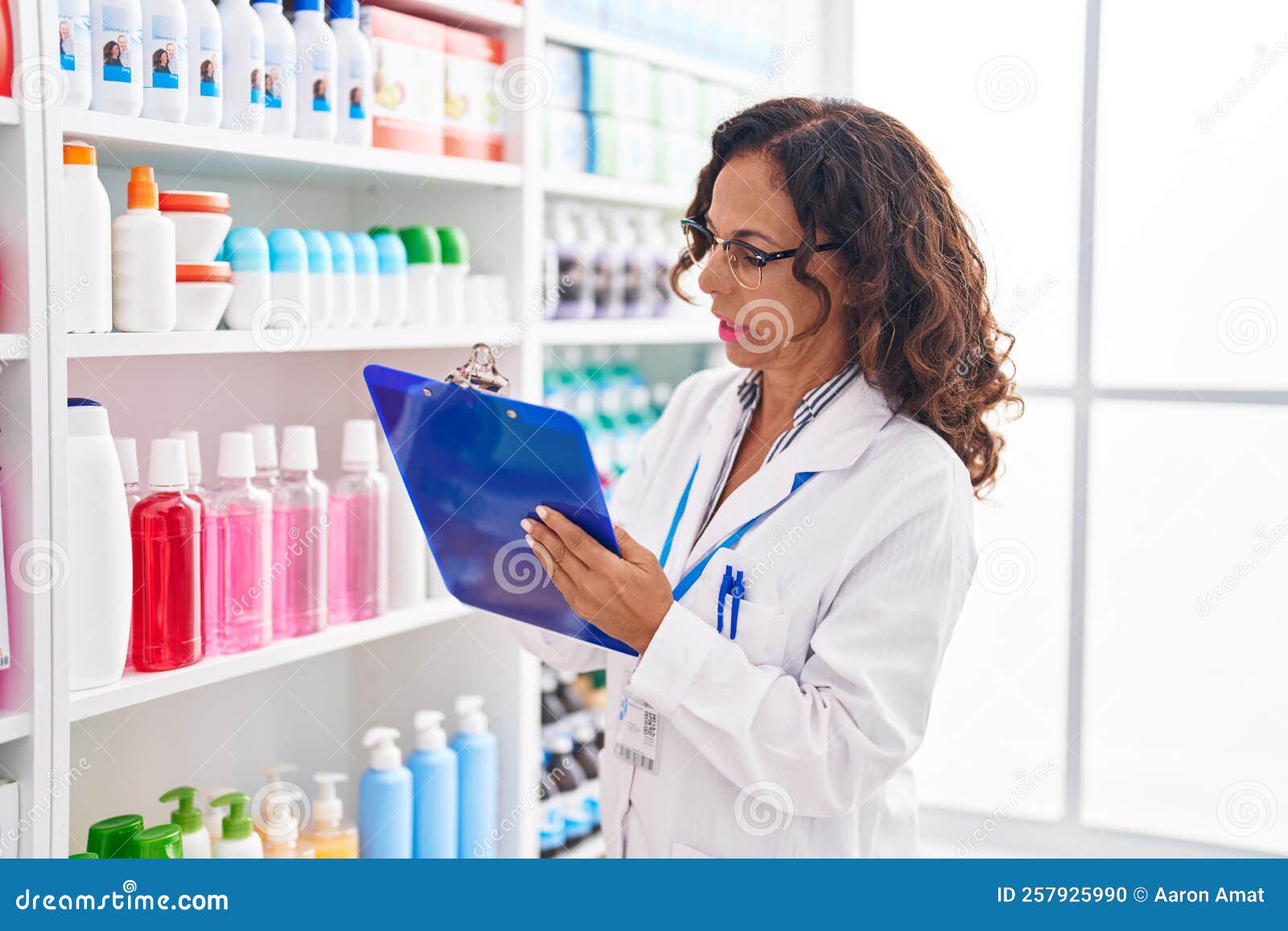 Middle Age Woman Pharmacist Writing on Document at Pharmacy Stock Photo ...