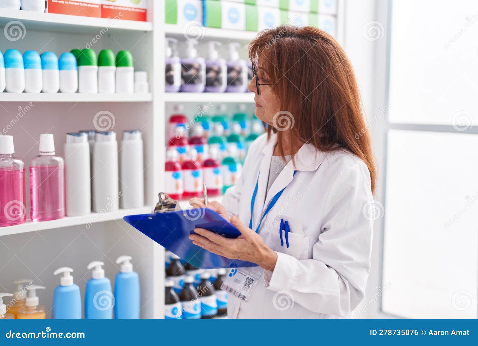 Middle Age Woman Pharmacist Writing on Document at Pharmacy Stock Photo ...