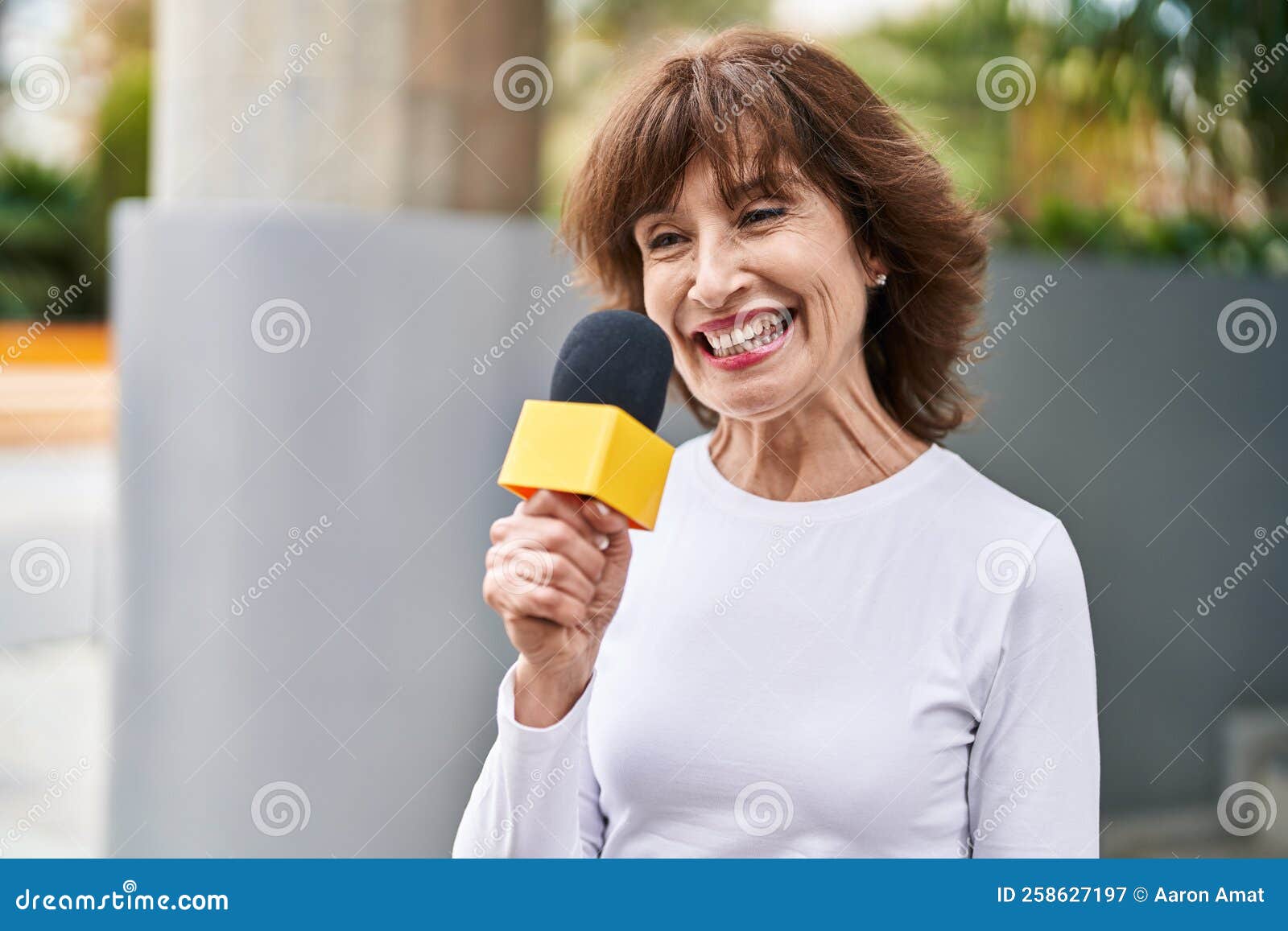 Middle Age Woman Reporter Working Using Microphone at Street Stock ...