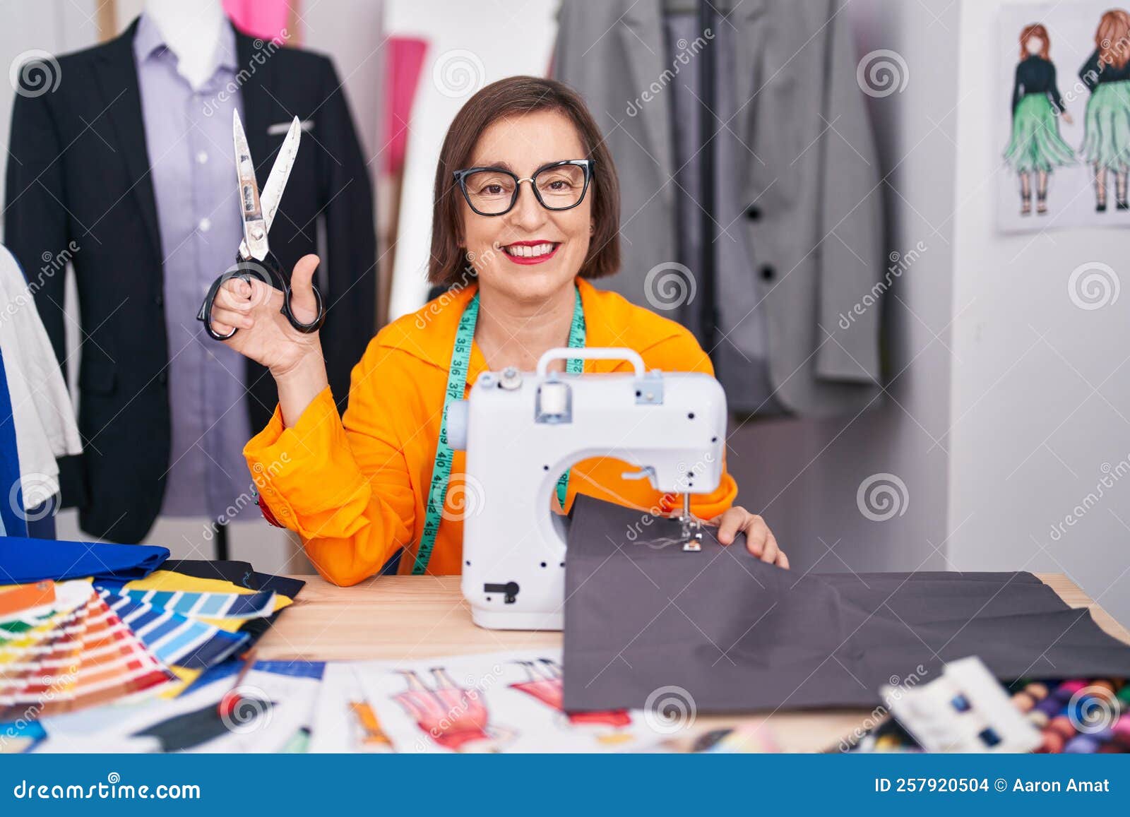 Middle Age Woman Tailor Using Sewing Machine Holding Scissors at Tailor ...