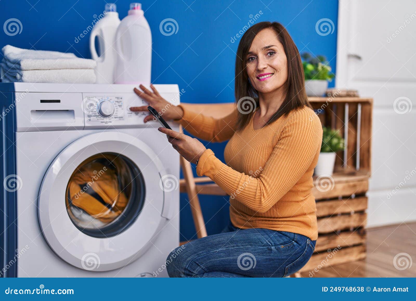 Middle Age Woman Turning on Washing Machine Using Smartphone at Laundry ...
