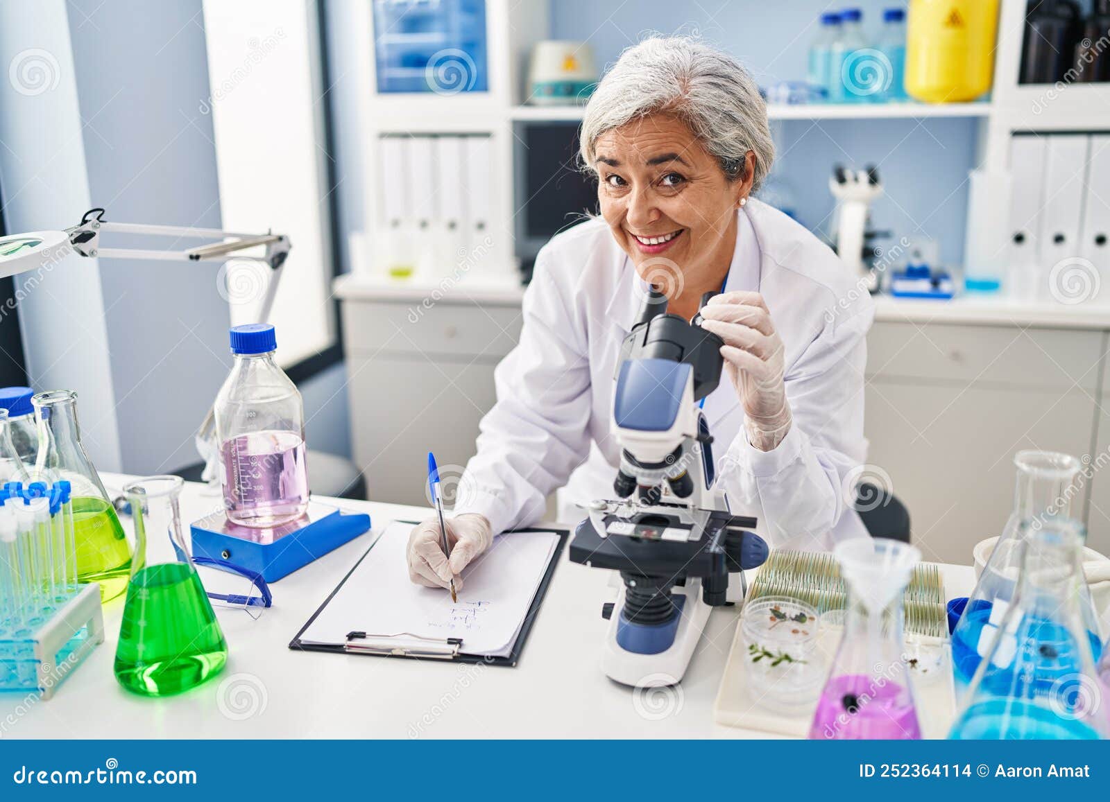Middle Age Woman Wearing Scientist Uniform Using Microscope at ...