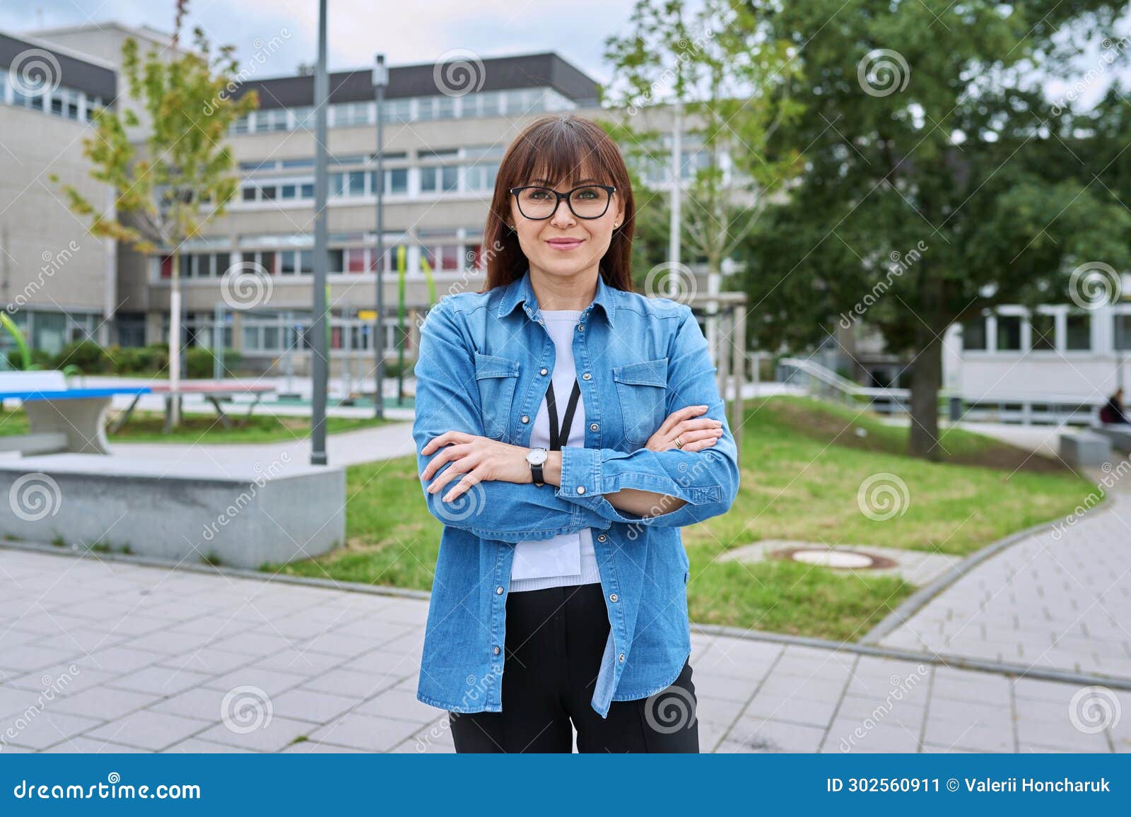Middle Aged Confident Woman Teacher With Crossed Arms Near School