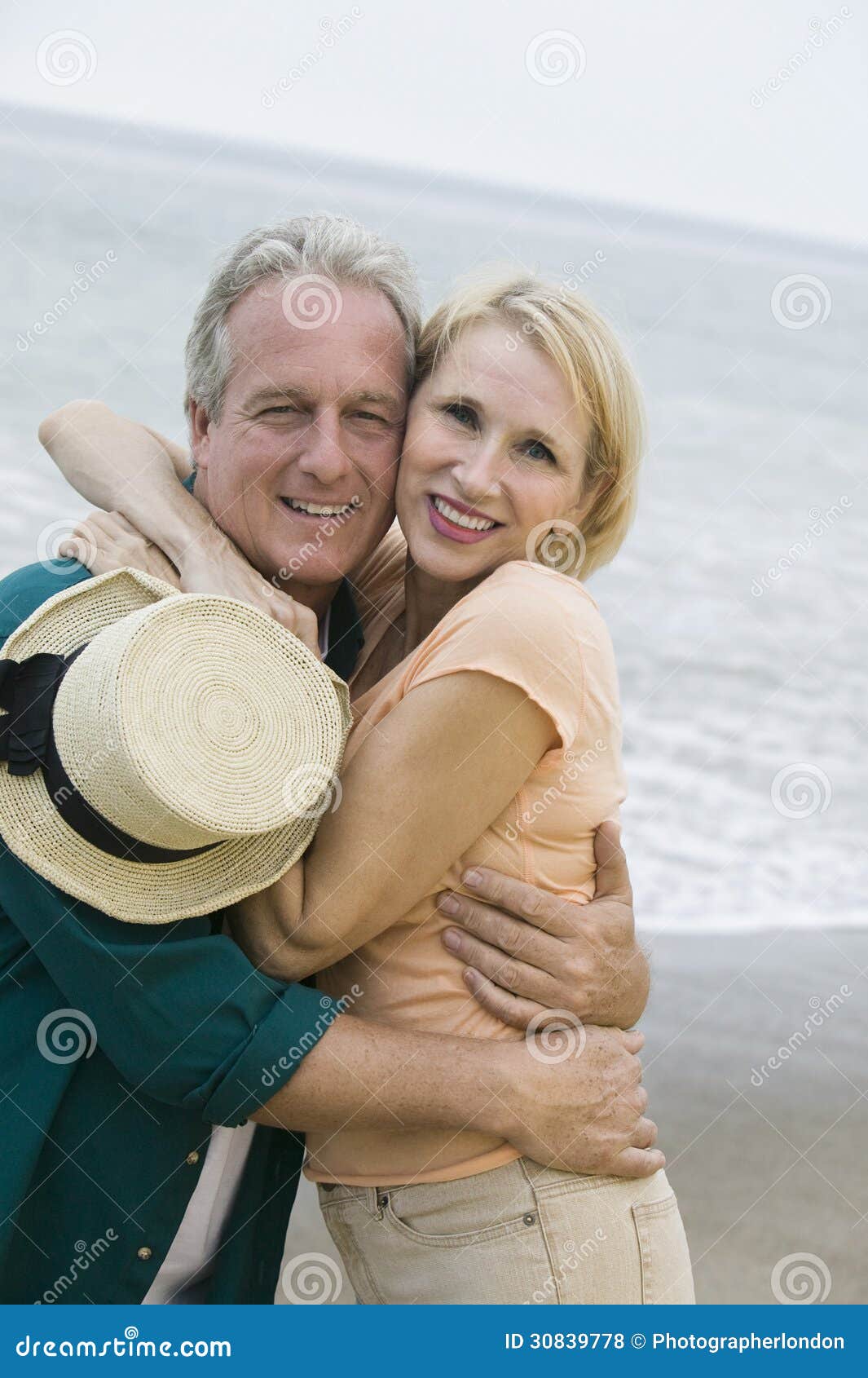 Middle-aged Couple Embracing on Beach and Looking at Camera Stock Photo ...
