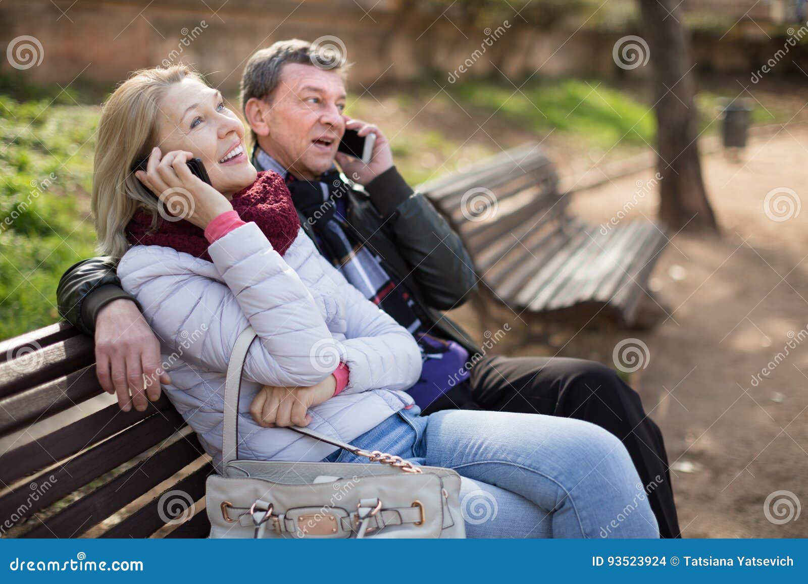 Middle Aged Couple Talking on the Phone on a Bench in the Park Stock ...