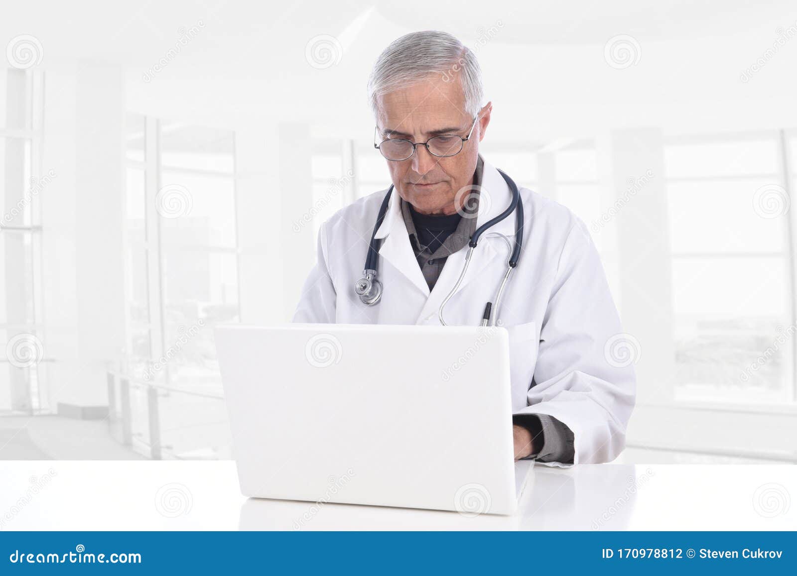 Middle Aged Doctor Standing at a Counter Using a Computer in a Modern ...