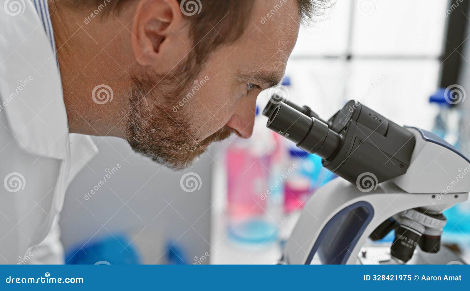 Middle-aged Man with a Beard Using a Microscope in a Laboratory Setting ...