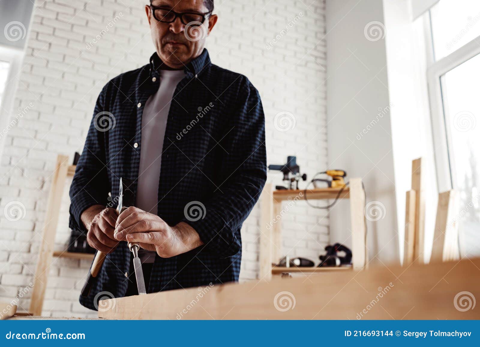 Middle-aged Man Carpenter Working in a Workshop with Chisel and Hammer ...