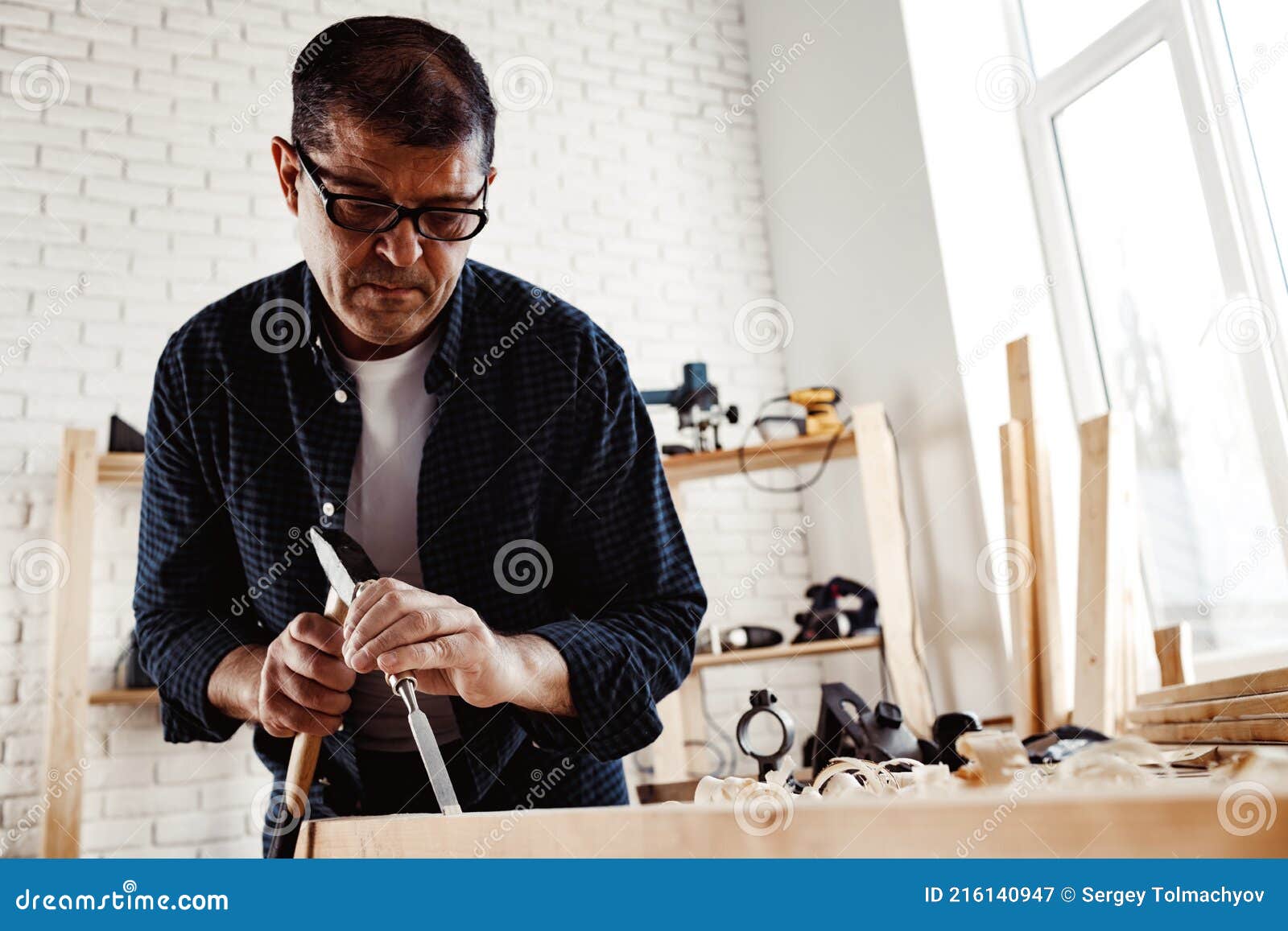 Middle-aged Man Carpenter Working in a Workshop with Chisel and Hammer ...