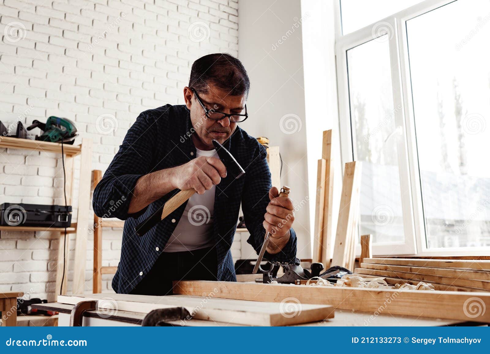 Middle-aged Man Carpenter Working in a Workshop with Chisel and Hammer ...