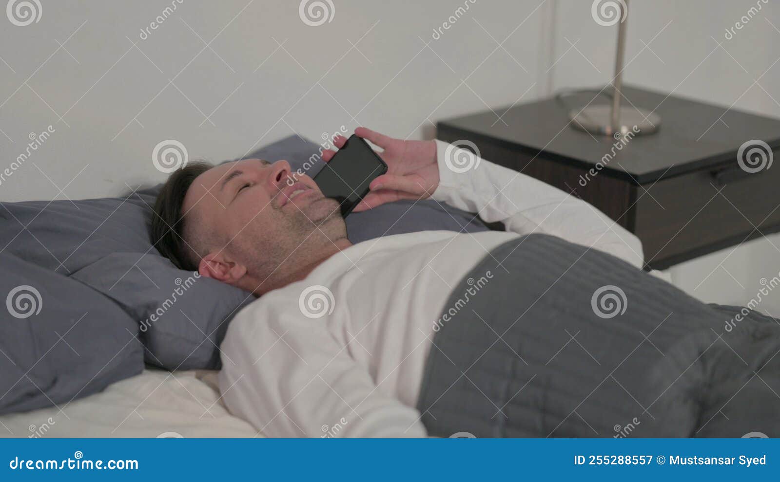 Casual Man Talking on Smartphone while Sleeping in Bed Stock Image ...