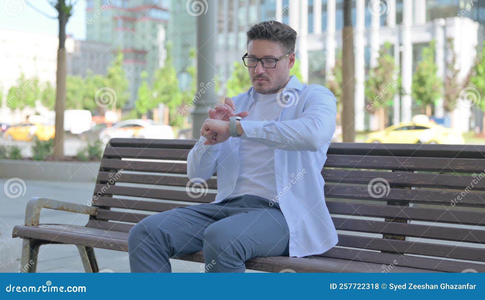 Man Using Smartwatch while Sitting Outdoor on Bench Stock Photo - Image ...