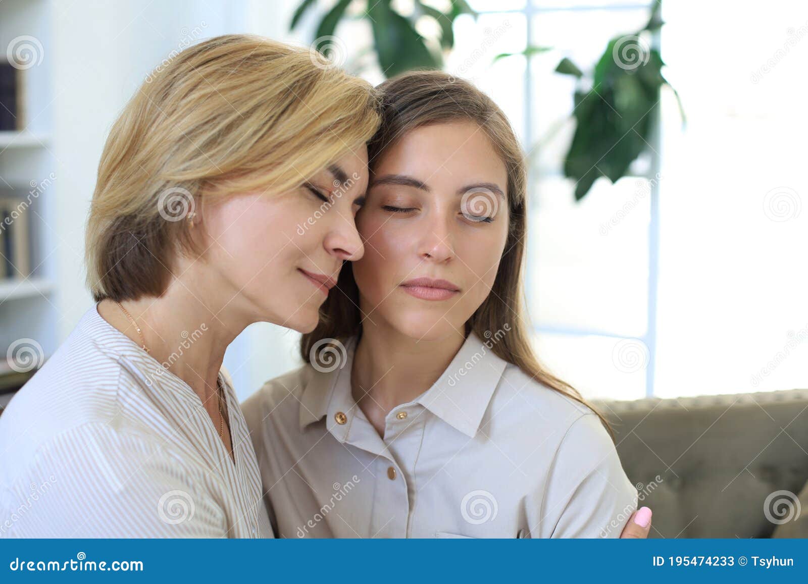 Middle Aged Mother And Daughter Talking On Sofa In Living Room Stock