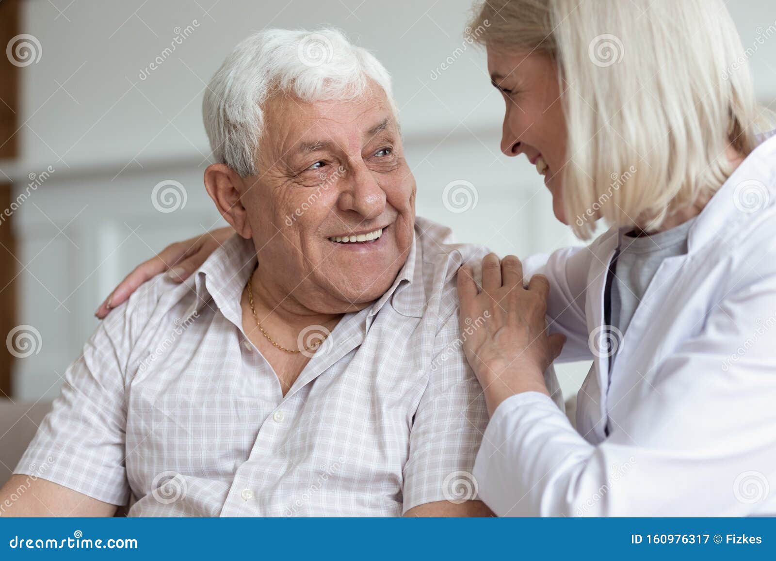 Middle Aged Nurse Hug Elderly Man Patient Sitting On Couch Stock Image