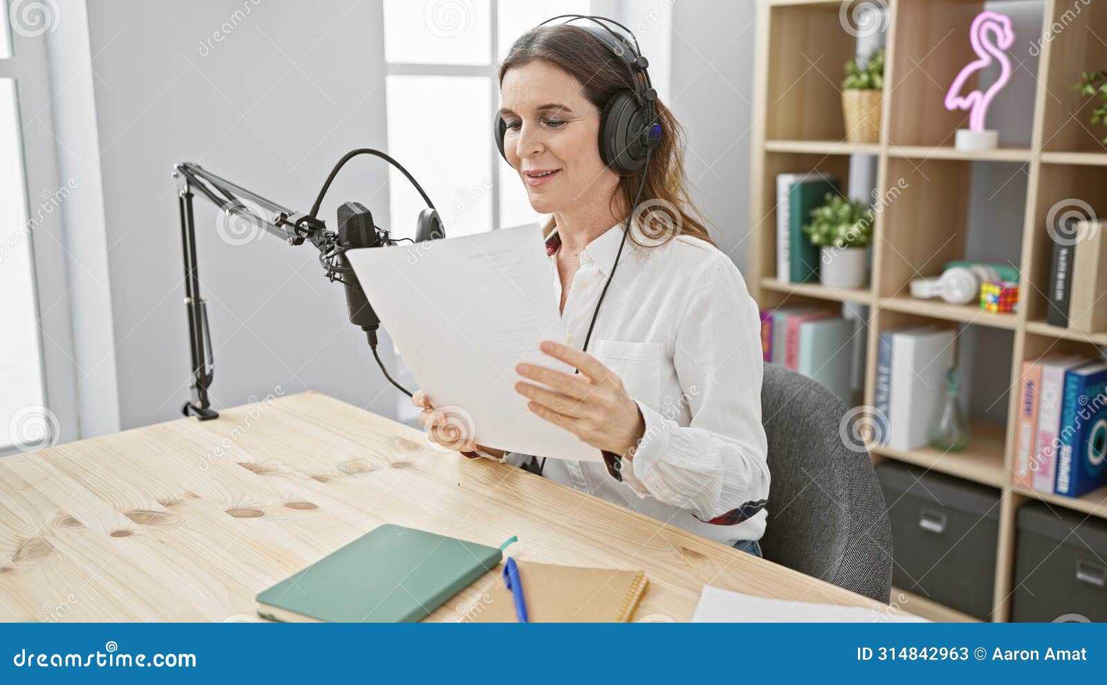 Middle-aged Woman with Headphones in Podcast Studio Reading a Script ...