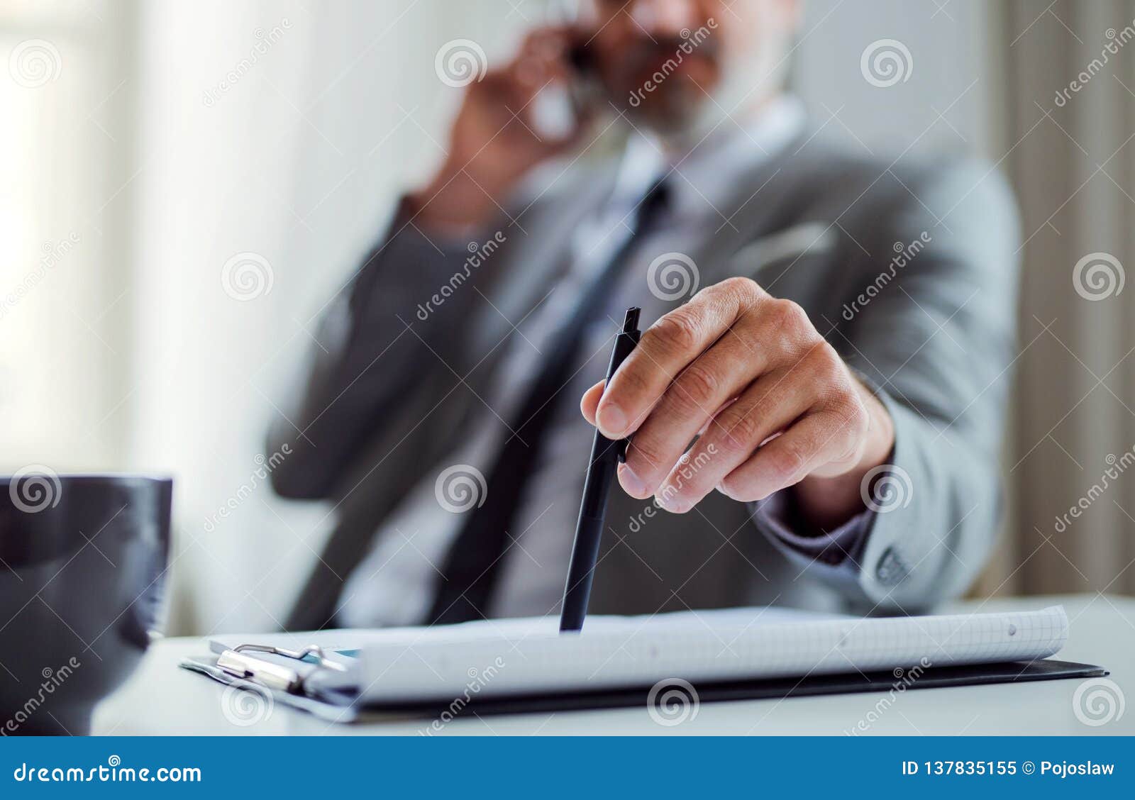 A Midsection of Businessman with Smartphone Sitting at the Table ...