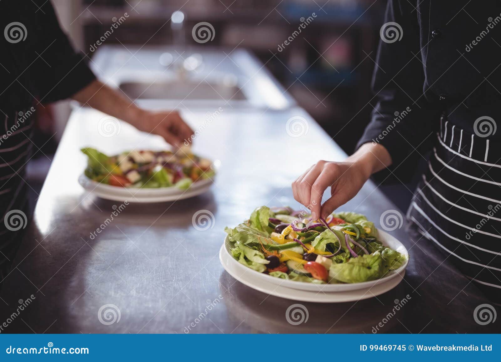 Midsection of Waiter and Waitress Preparing Fresh Salad in Commercial ...