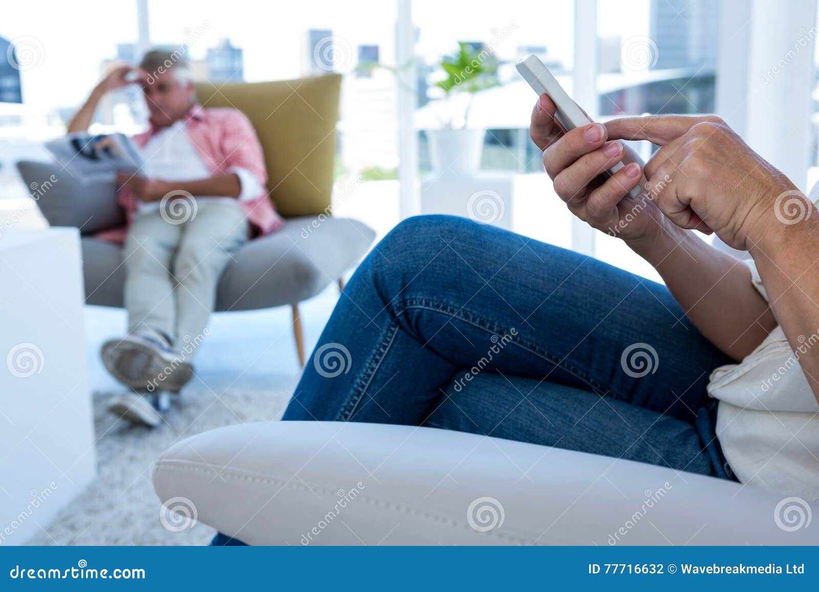 Midsection of Woman Using Mobile Phone while Man Reading Newspaper ...