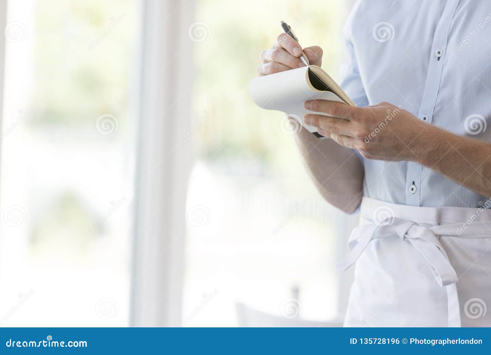 Midsection of Young Waiter Writing on Notepad while Standing at ...
