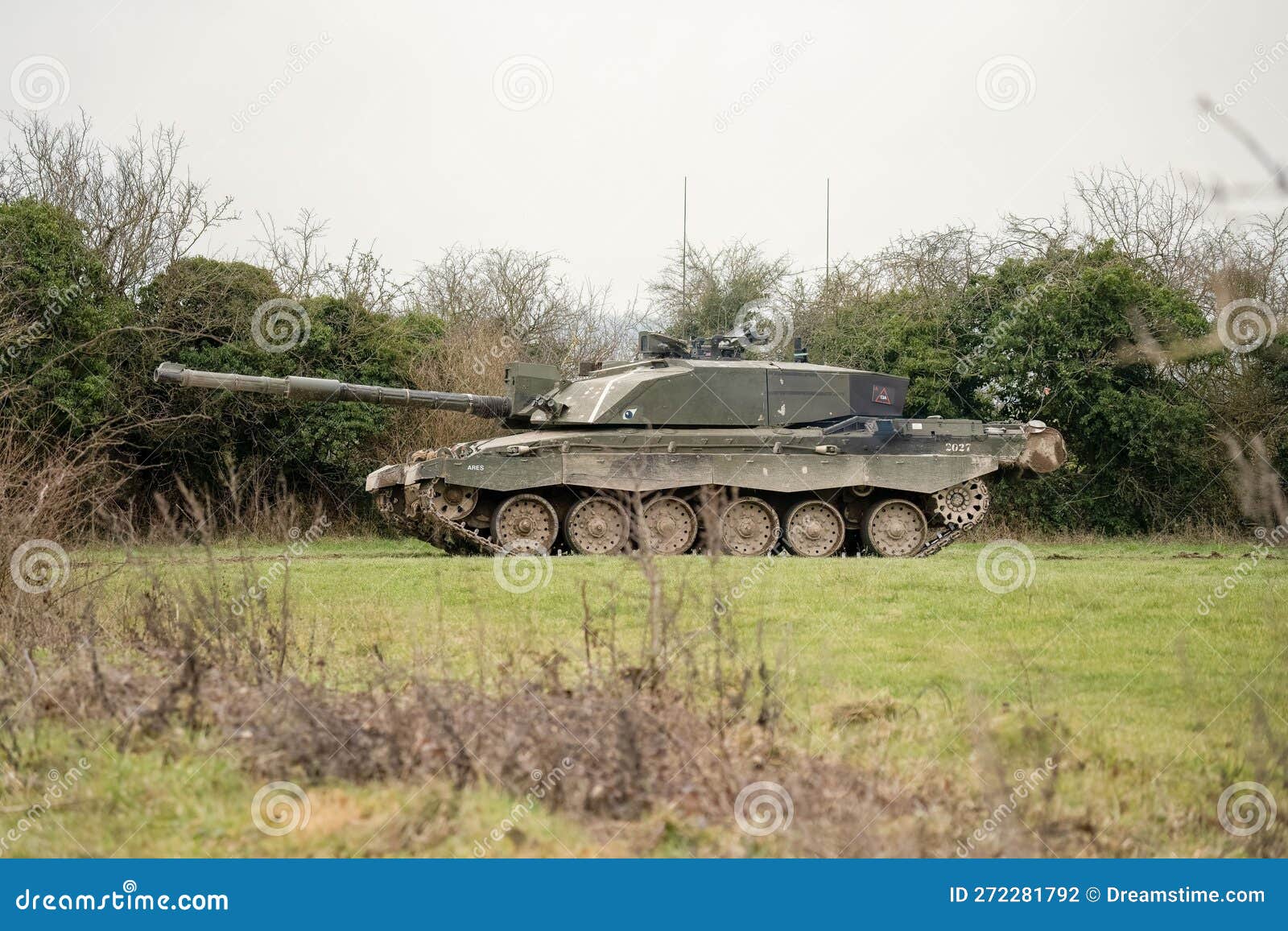 Military Tank Parked in a Grassy Meadow in Front of a Cluster of Trees ...